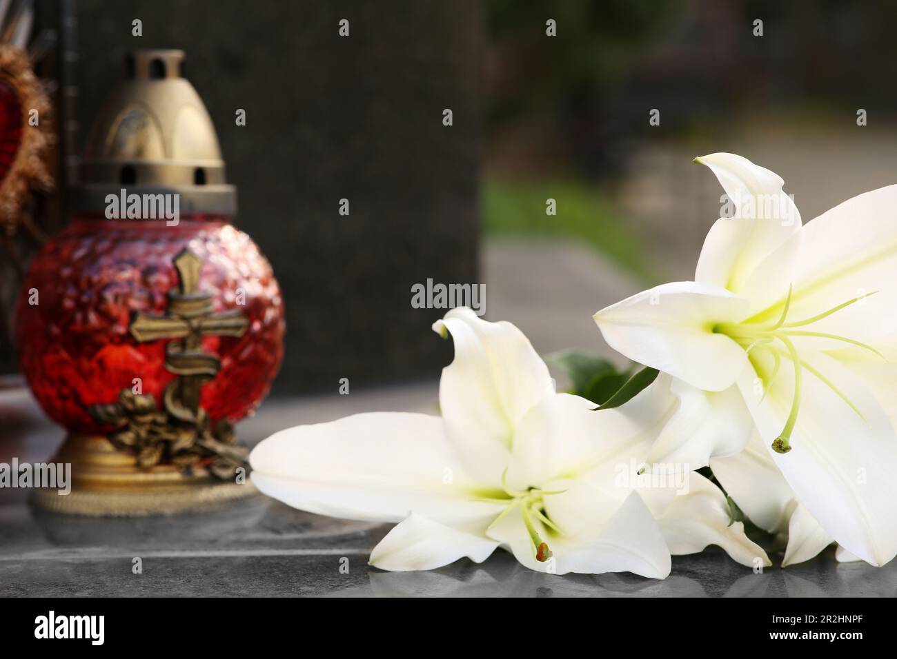 White lilies and grave light on grey granite tombstone outdoors, closeup. Funeral ceremony Stock ...