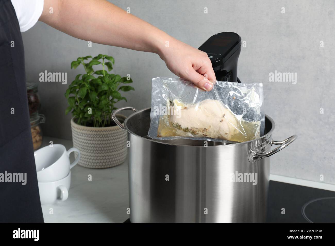 Woman taking out vacuum packed meat from pot in kitchen, closeup ...
