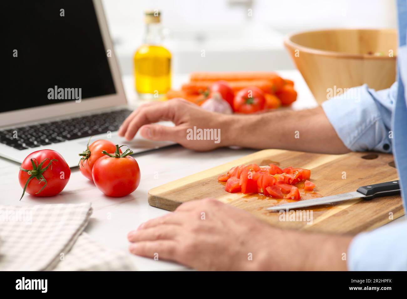 Man making dinner while watching online cooking course via laptop in ...