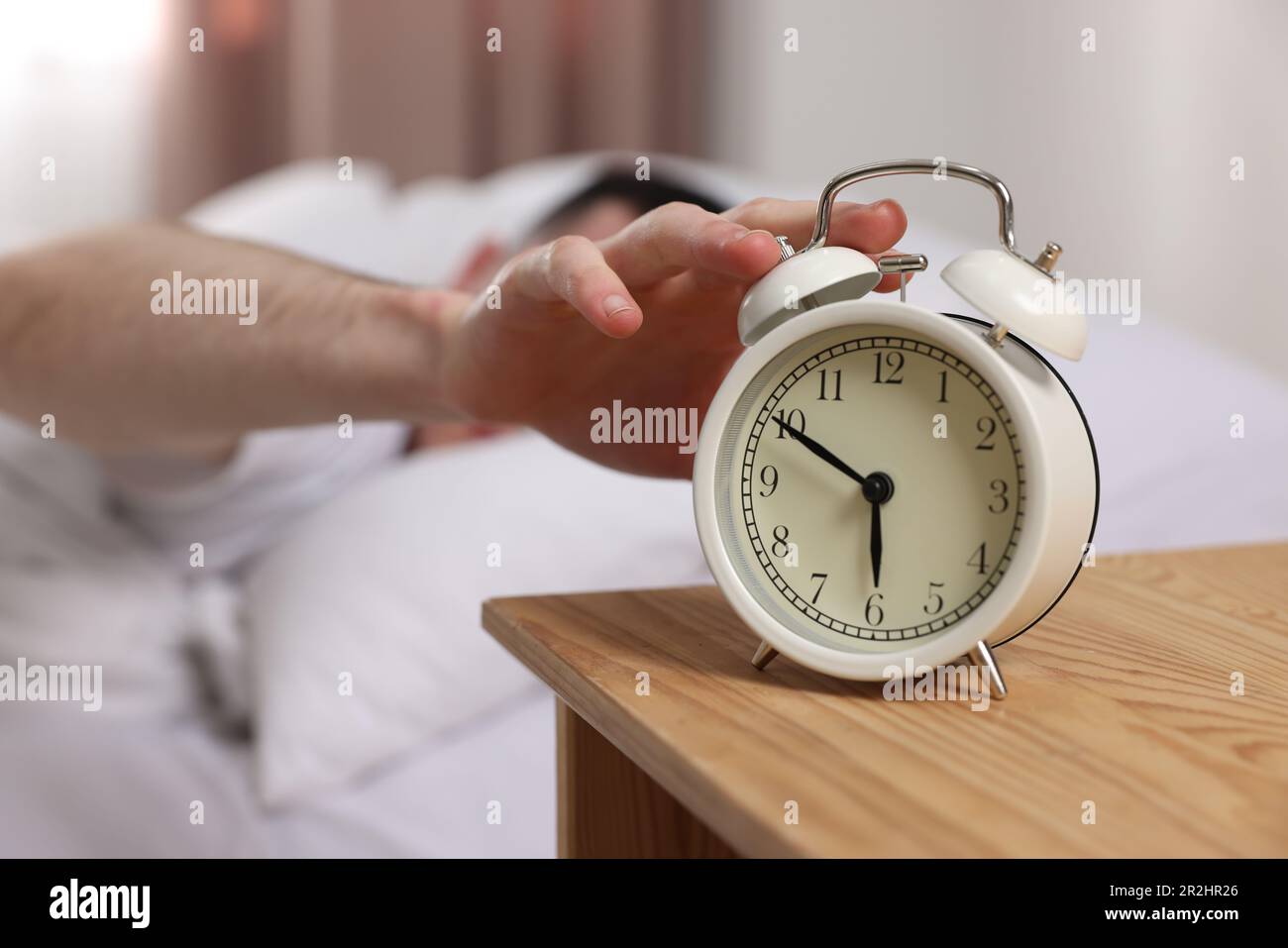 Man turning off alarm clock in bedroom, focus on hand Stock Photo - Alamy