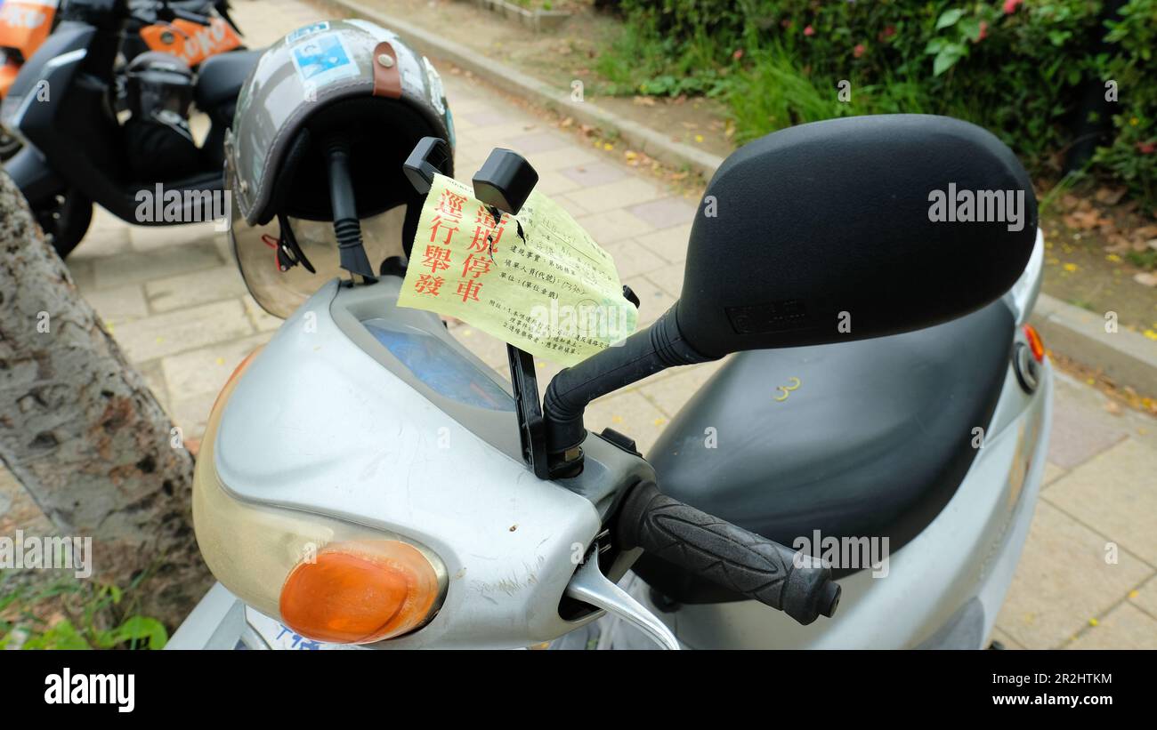 Motor scooter with parking ticket in Kaohsiung, Taiwan; yellow slips ...