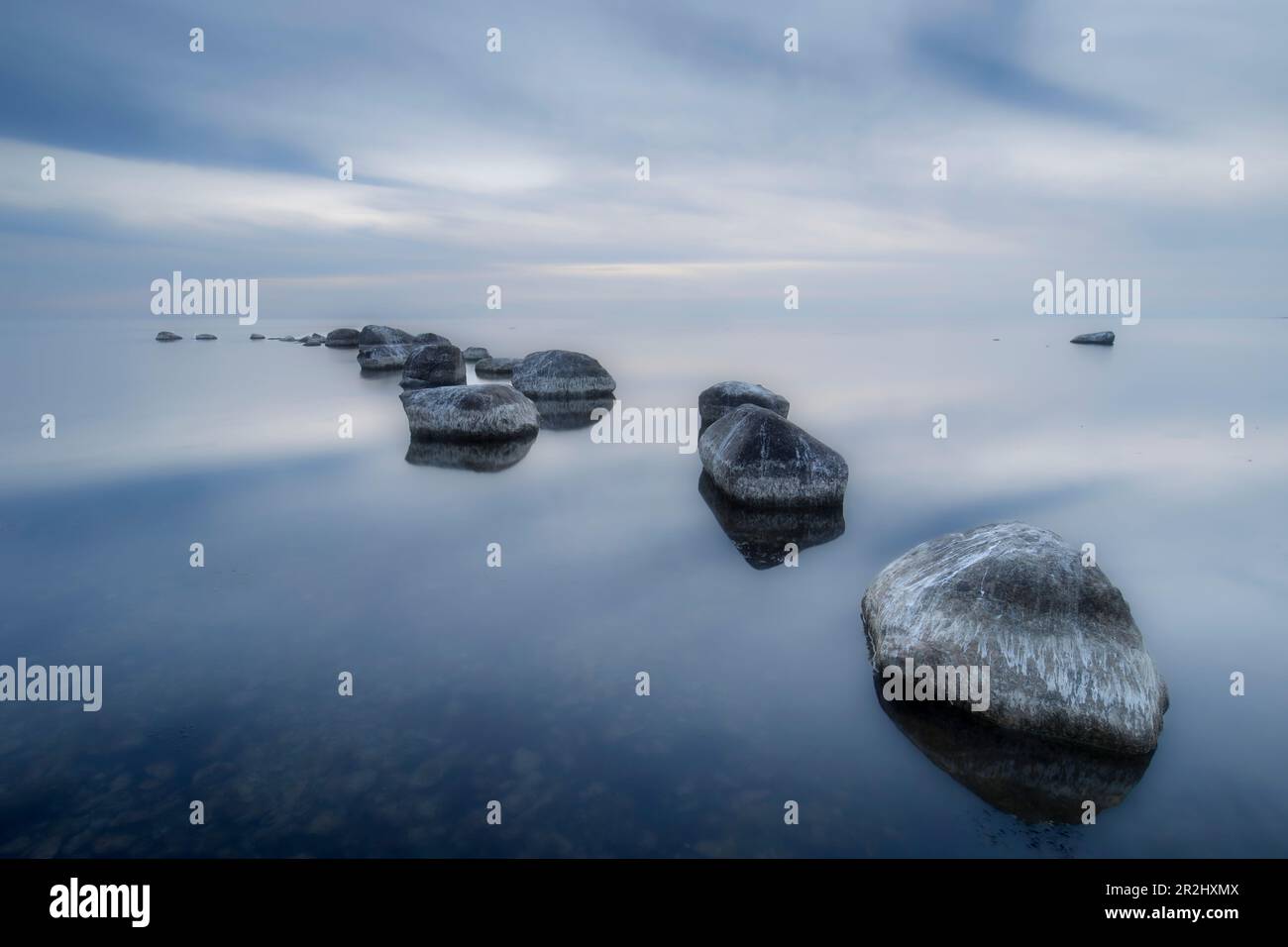 Stones in the water lie in a slight arc. Smooth water surface. Clouds ...