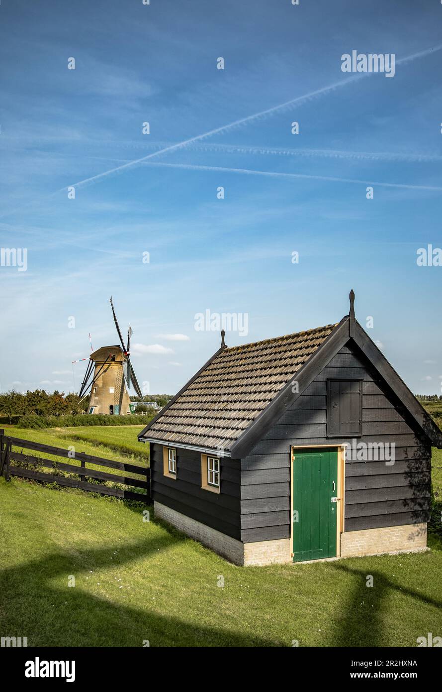 Kindedijk windmill in the Netherlands in the background with an old farmhouse with a green door ...