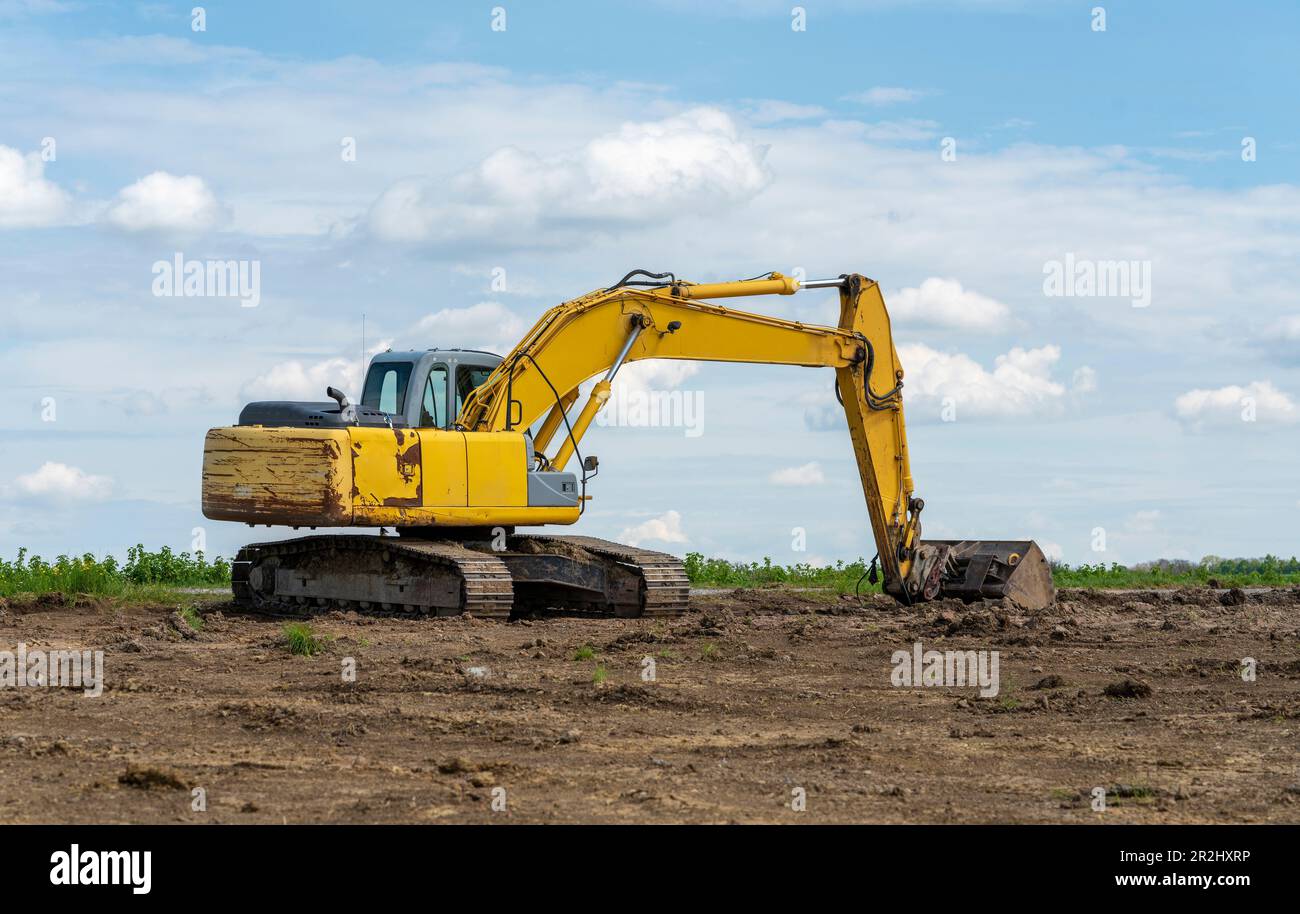 Rundown yellow excavator resting on earthen ground Stock Photo - Alamy
