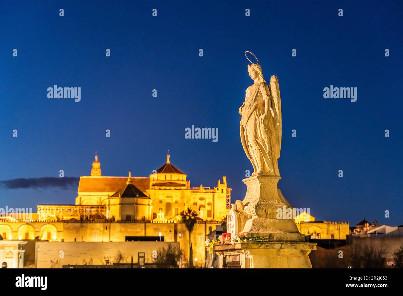 Statue of Archangel Raphael on the Roman Bridge and Mezquita at dusk ...