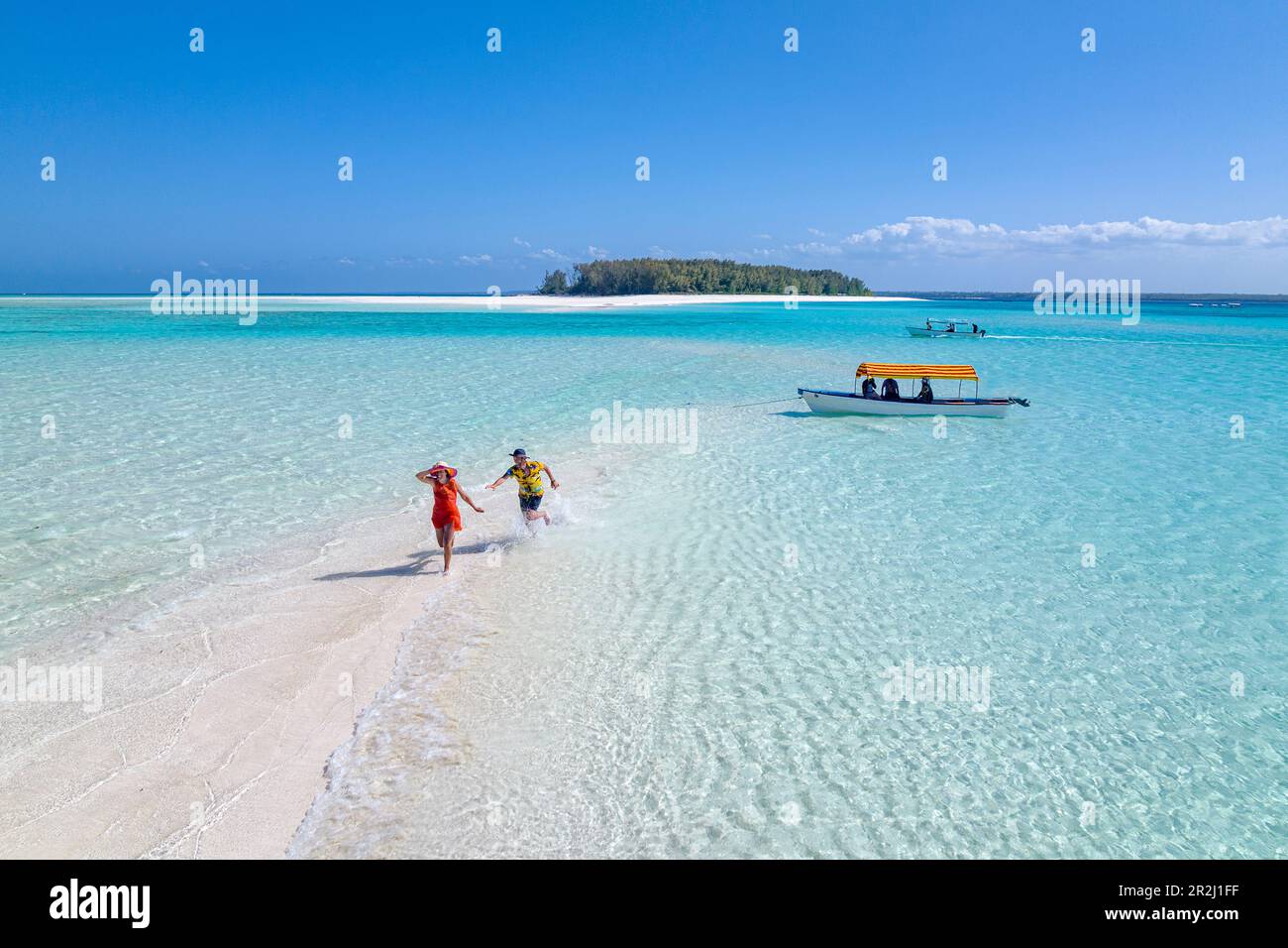 Cheerful man and woman having fun chasing each others on a tropical beach, aerial view, Zanzibar ...