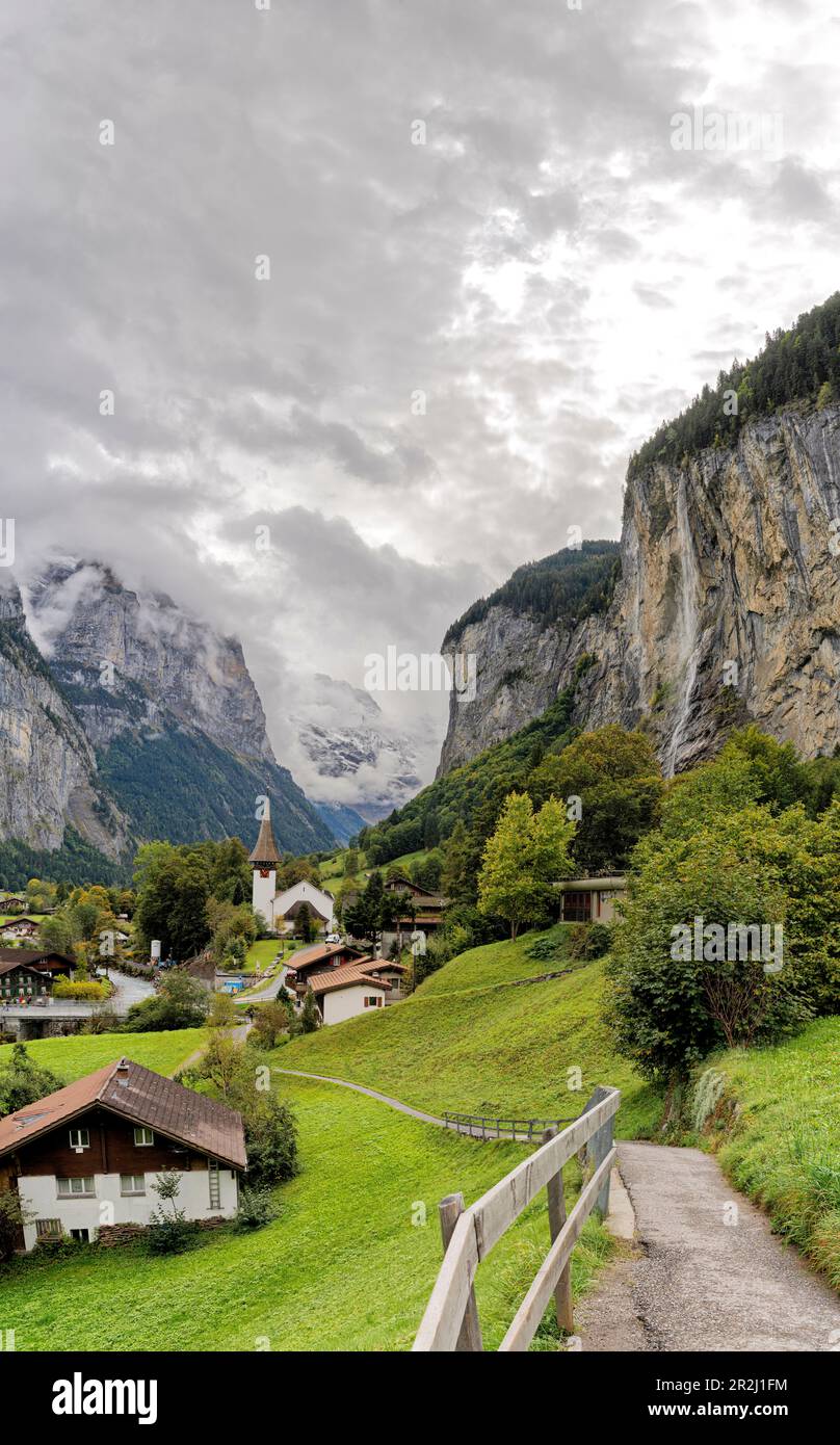 Path among green meadows of the alpine village of Lauterbrunnen with ...