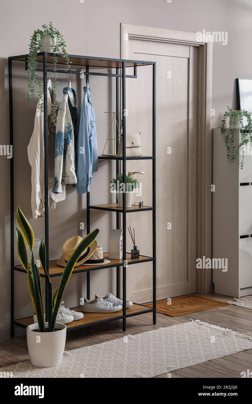 Shelving unit with clothes and accessories in modern hall Stock Photo ...