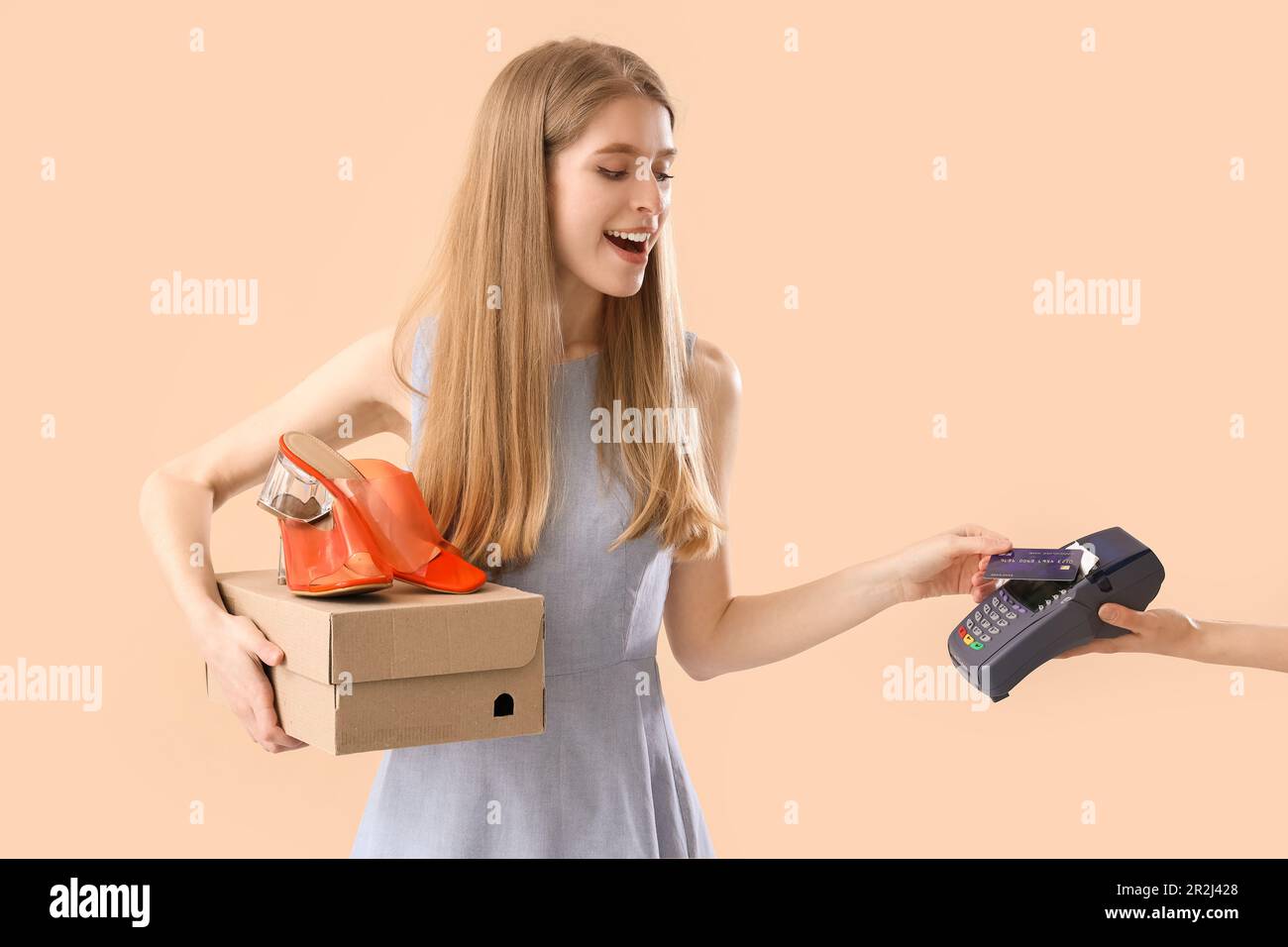 Young woman with shoes and credit card paying on beige background Stock ...