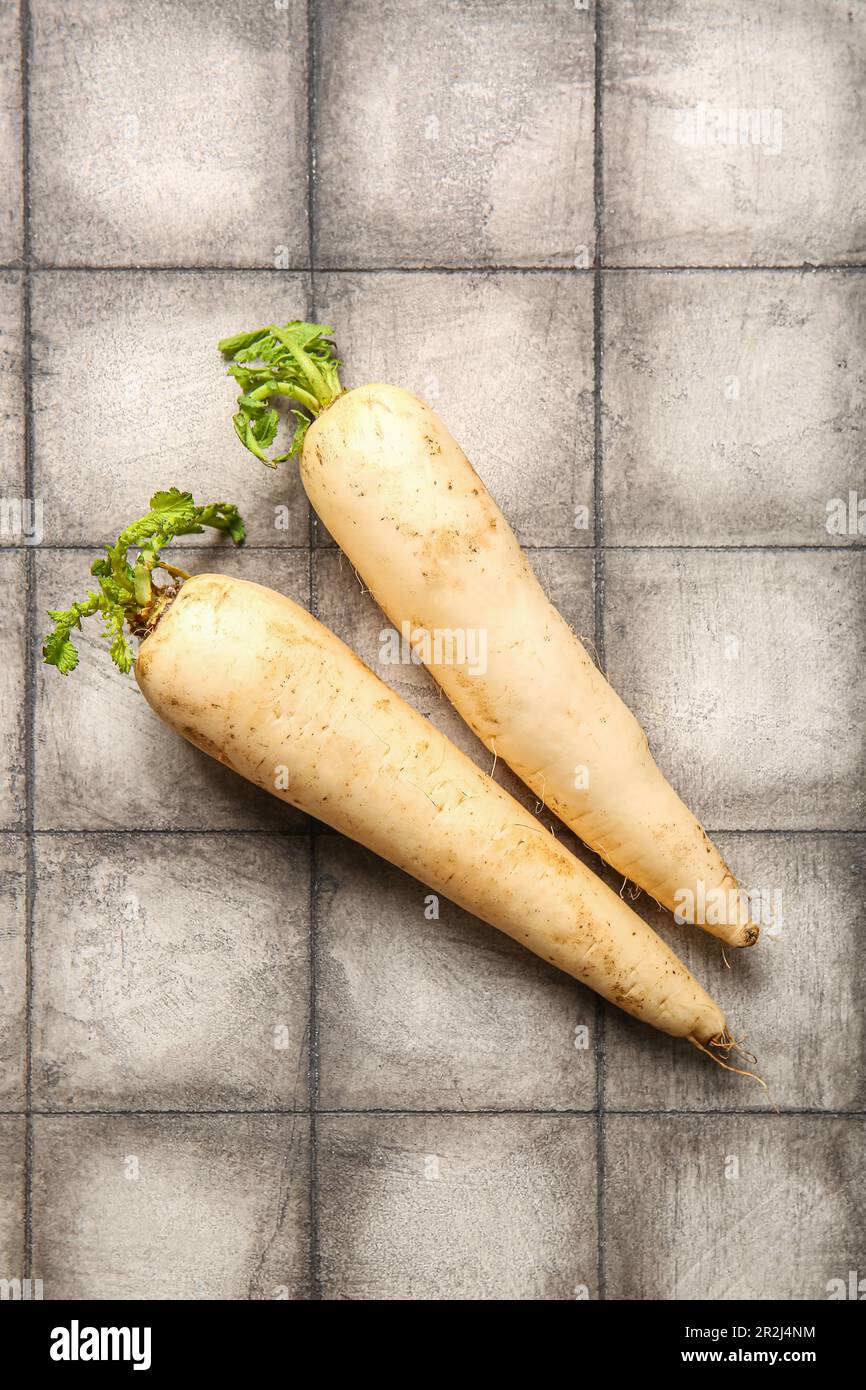 Fresh daikon radishes on grey tile background Stock Photo - Alamy