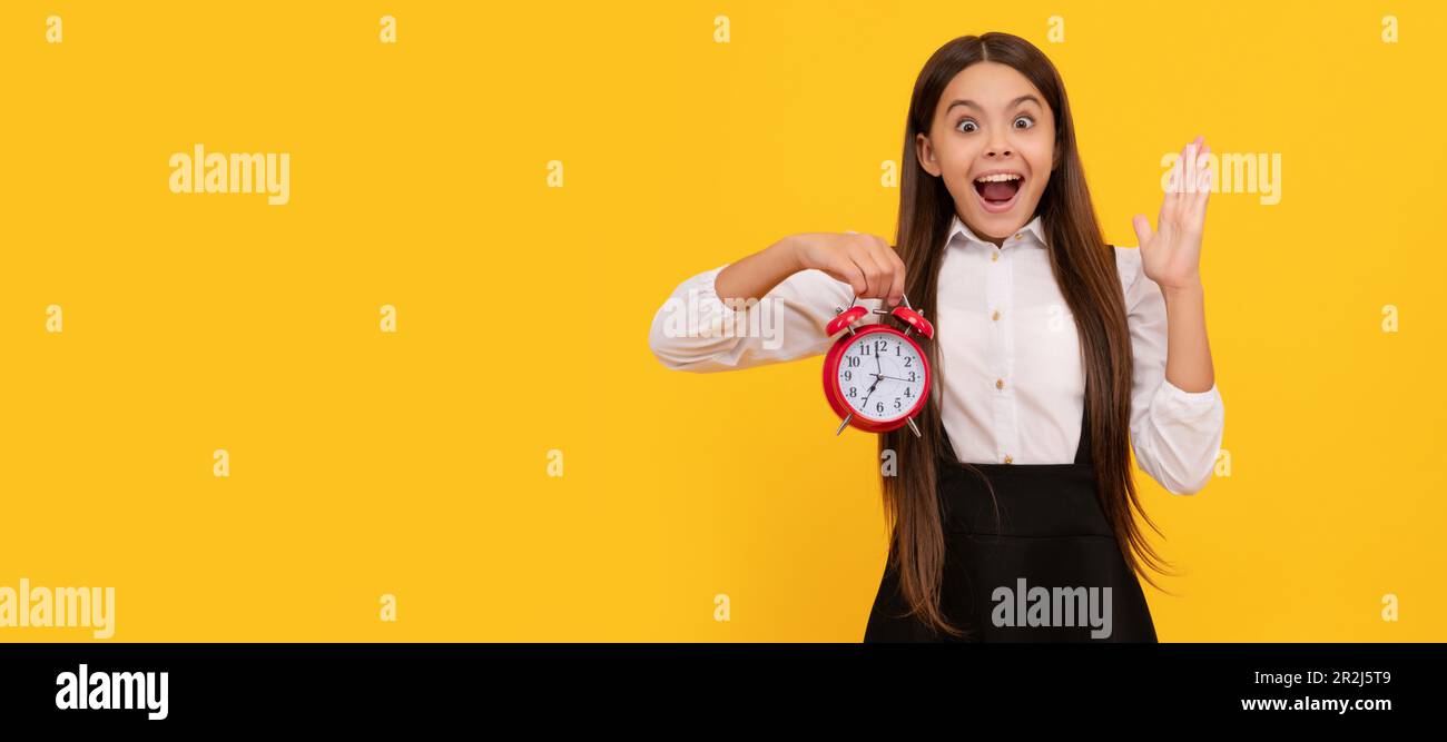 surprised kid in school uniform with alarm clock showing time on yellow ...