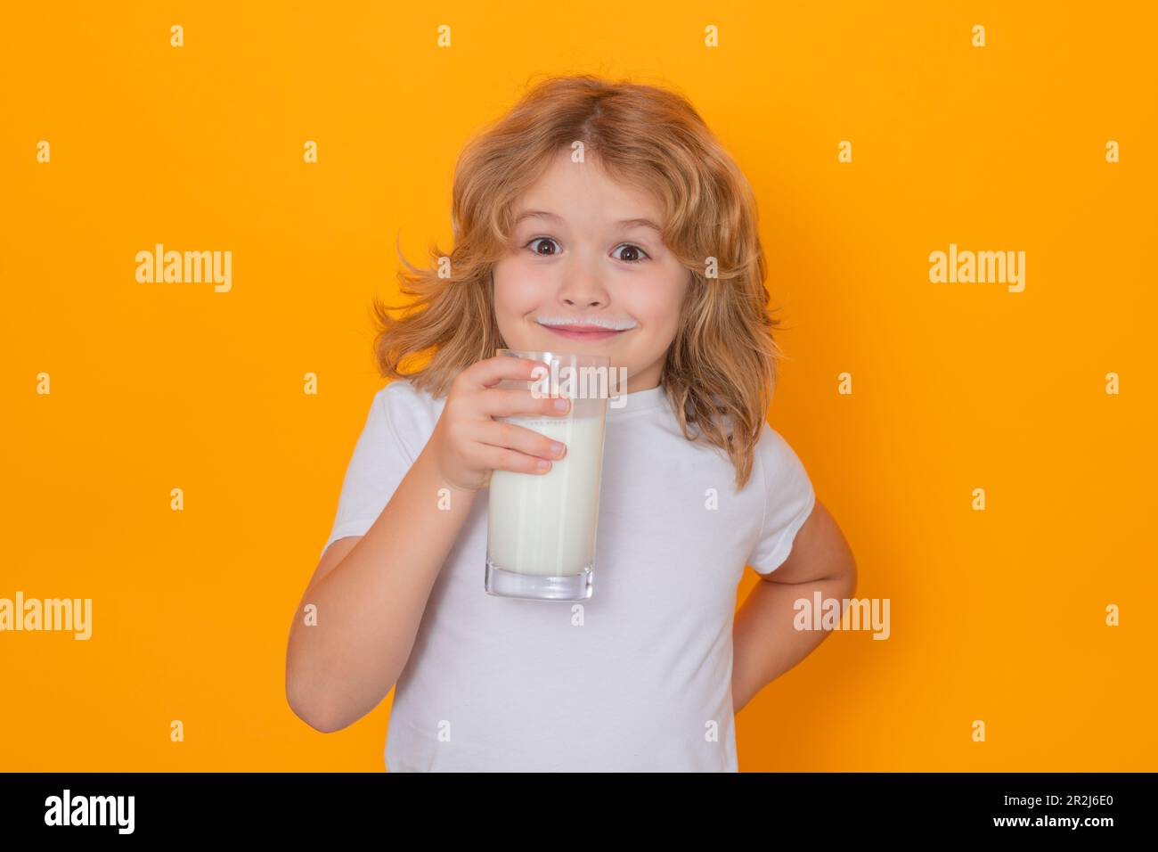 Child with glass of milk on studio yellow background. Kid with milk ...