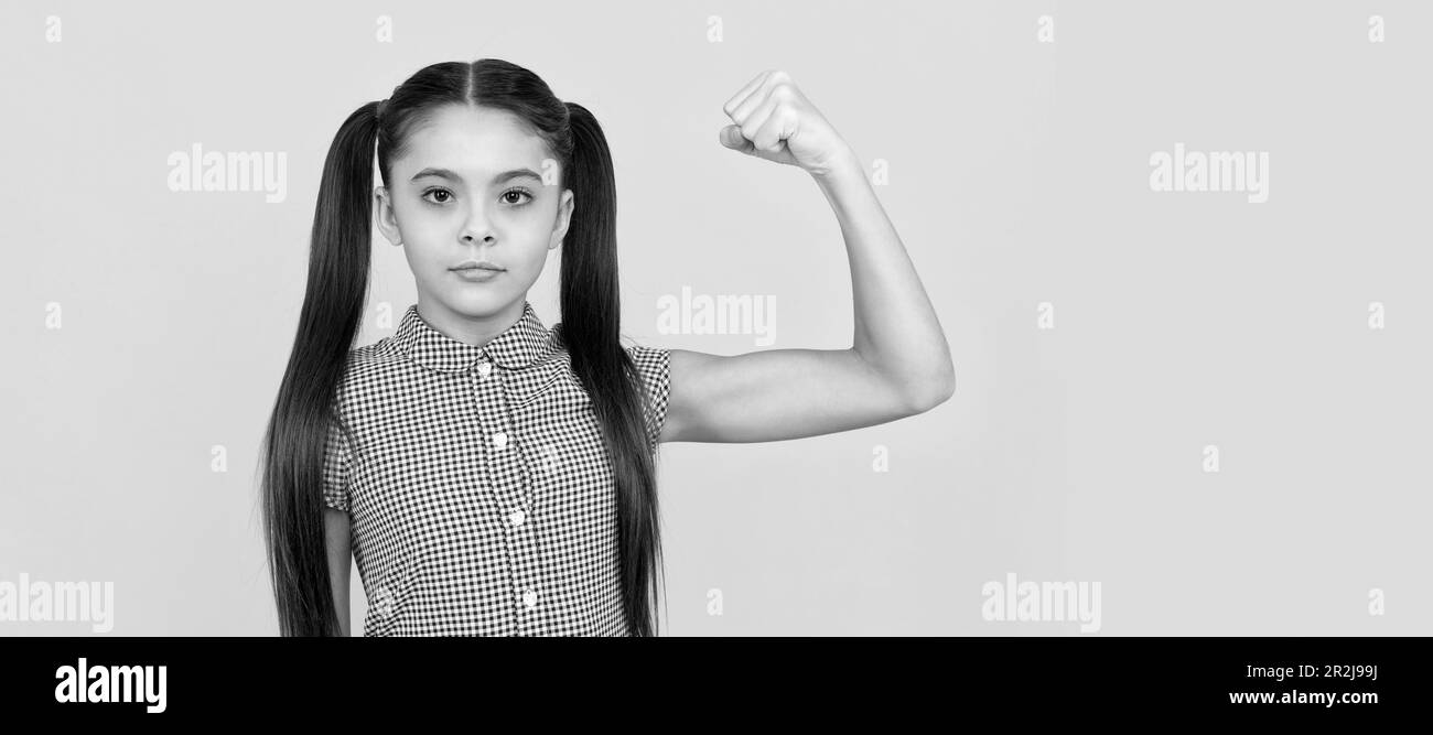 Serious girl child show power gesture flexing arm yellow background ...