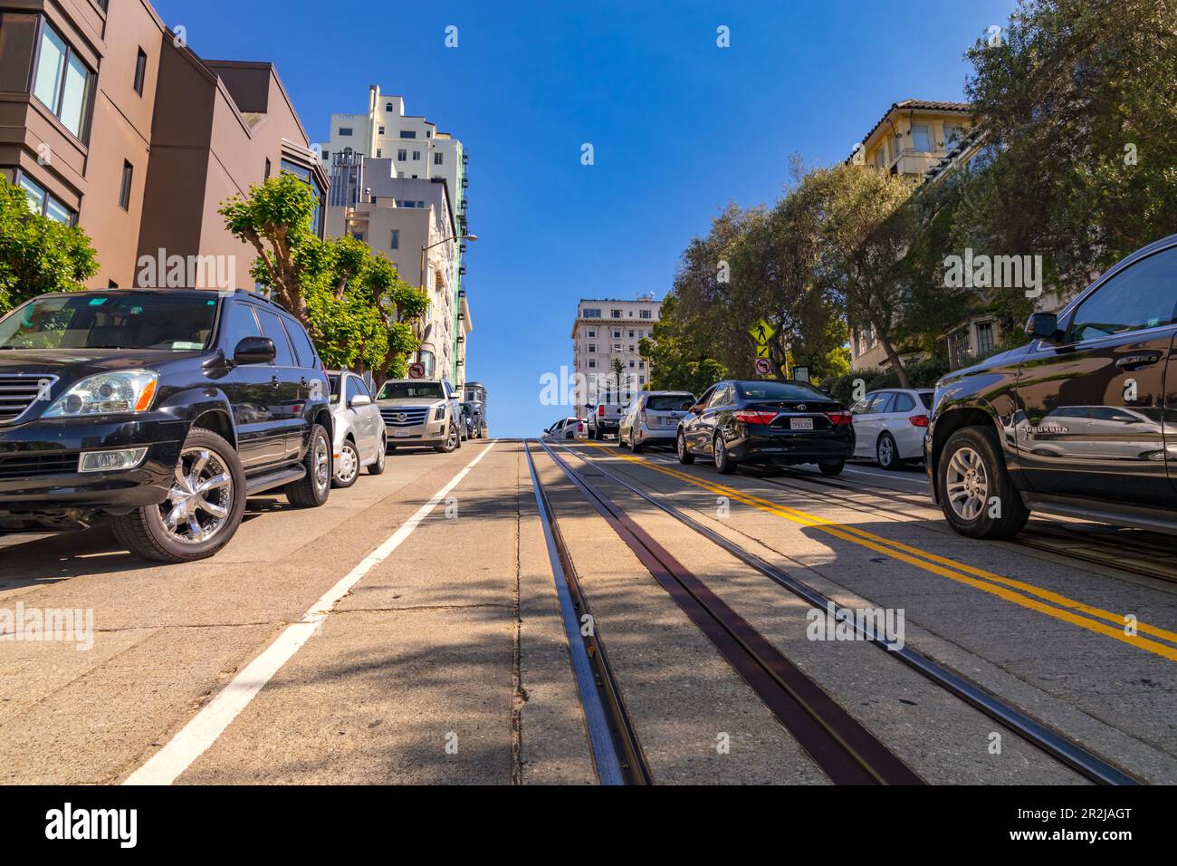 The steep streets of San Francisco with tram rails against a blue sky ...