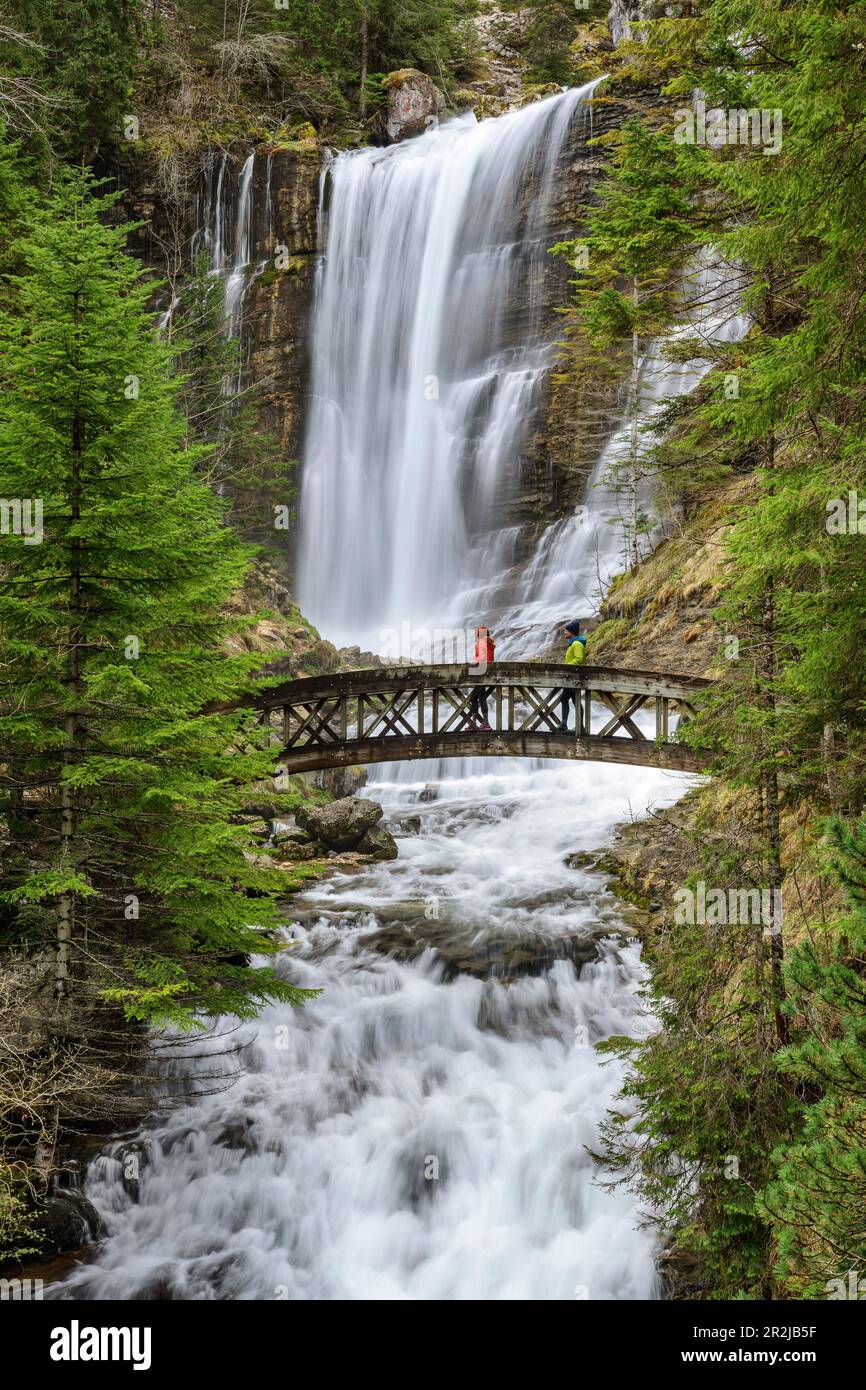 Two people hiking walking across bridge with Cirque de Saint-Meme ...