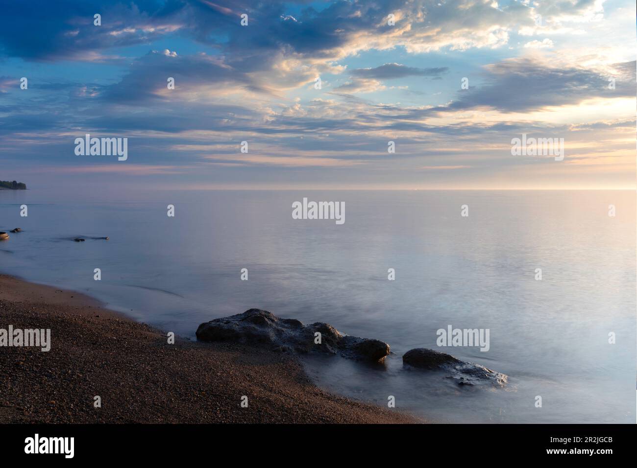 A rocky shore along Lake Huron with cloudy skies and a hint of sunrise ...