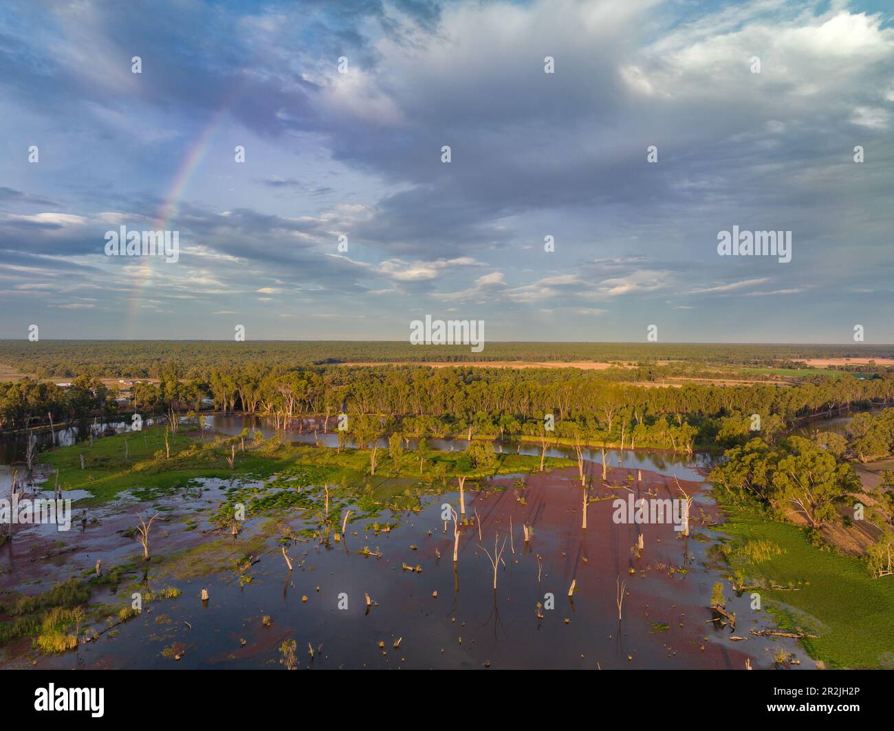 Aerial view of a rainbow and cloud formations over a rural wetland at ...