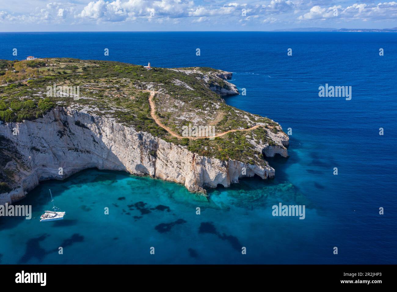 Aerial view of a catamaran in secluded bay with cliffs behind, Volimes ...