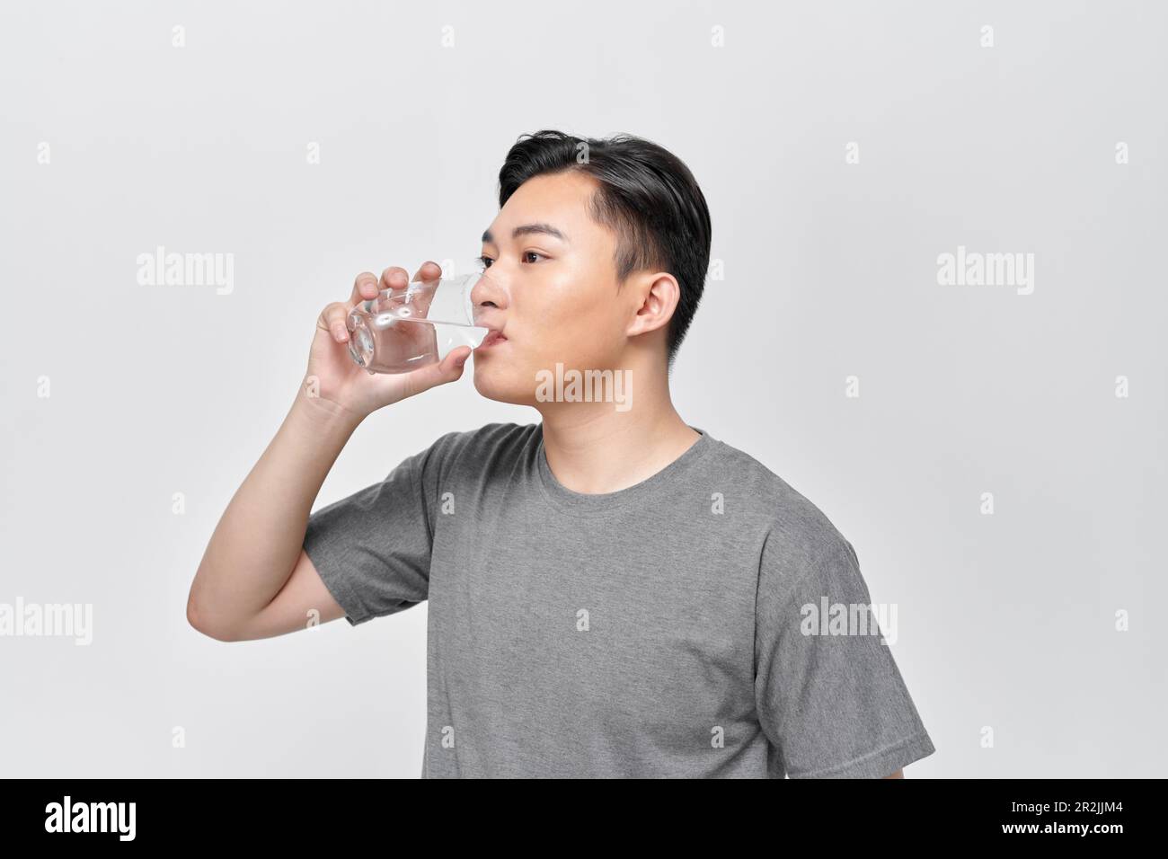 Young man hydrating himself with a glass of water Stock Photo - Alamy
