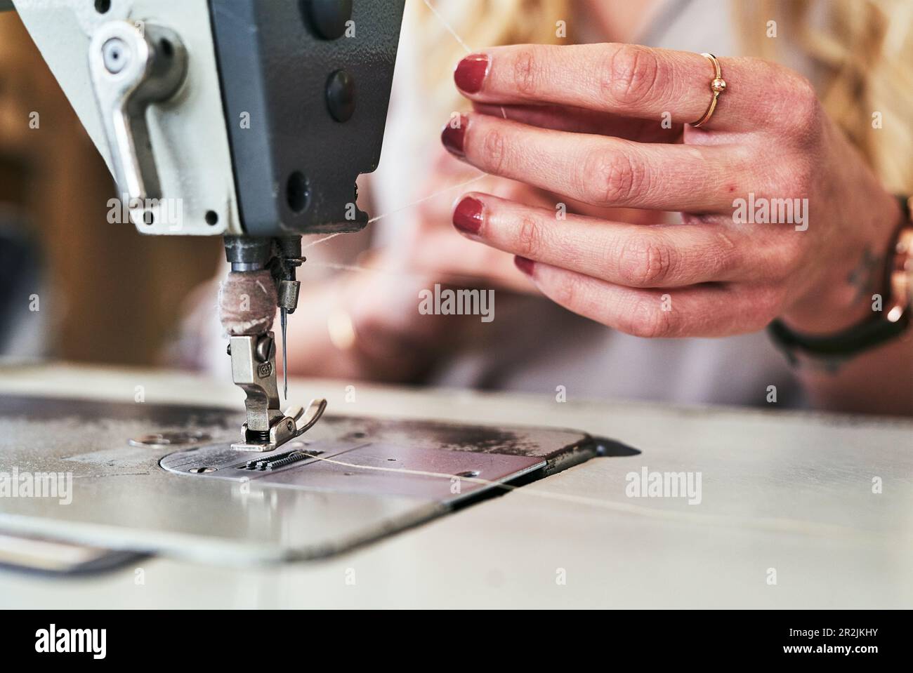 Sewing machine, seamstress woman hands and fashion designer with thread ...