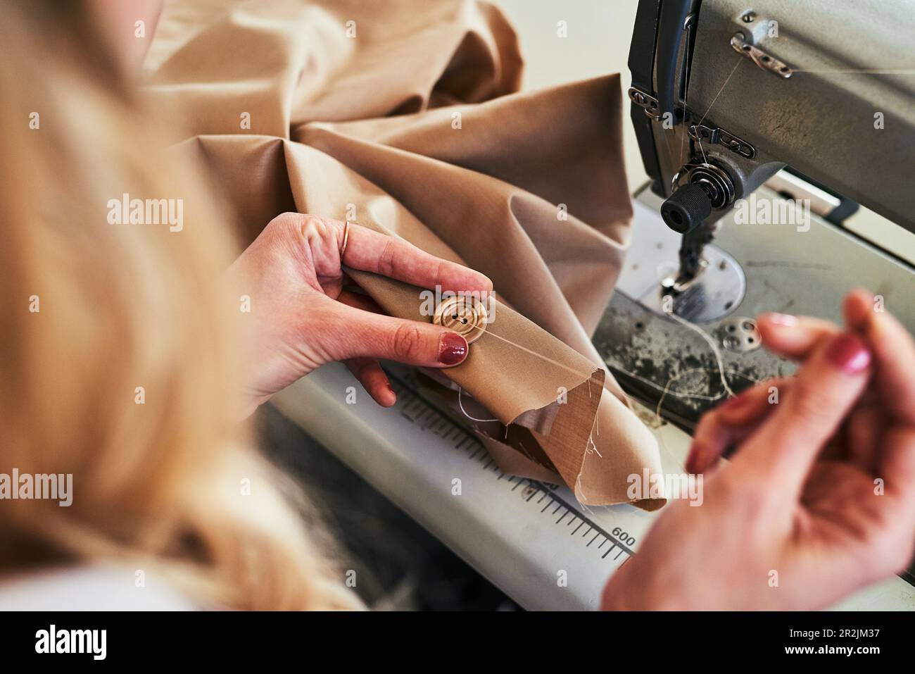 Sewing machine, woman hands and fashion designer with button and thread ...