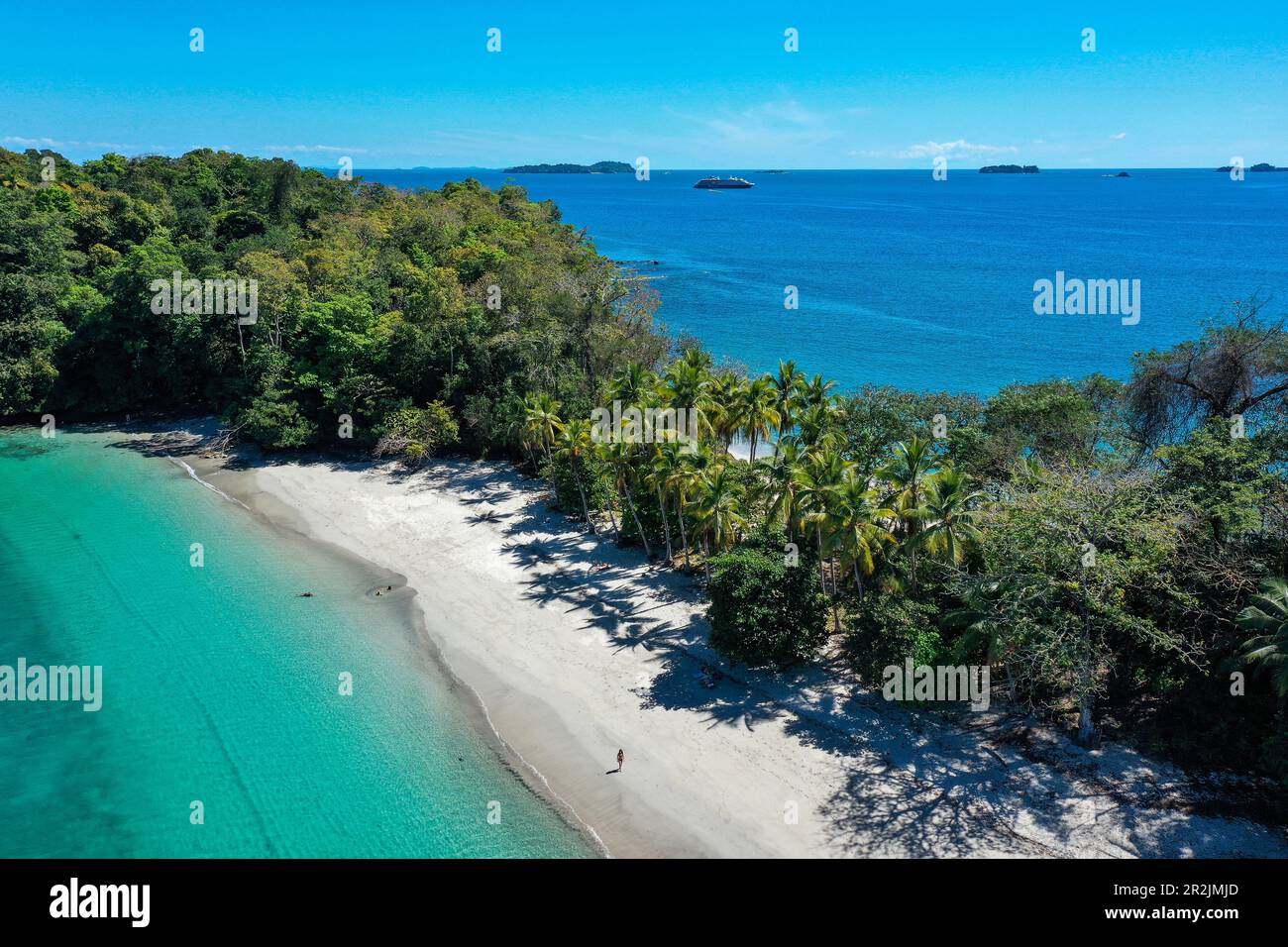 Aerial view of woman walking on pristine beach with expedition cruise ...