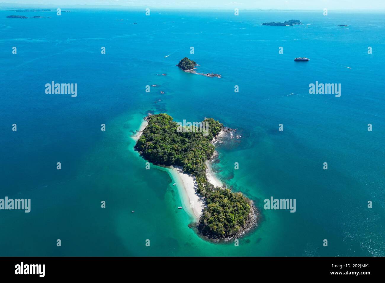 Aerial view of pristine beaches on island with expedition cruise ship ...