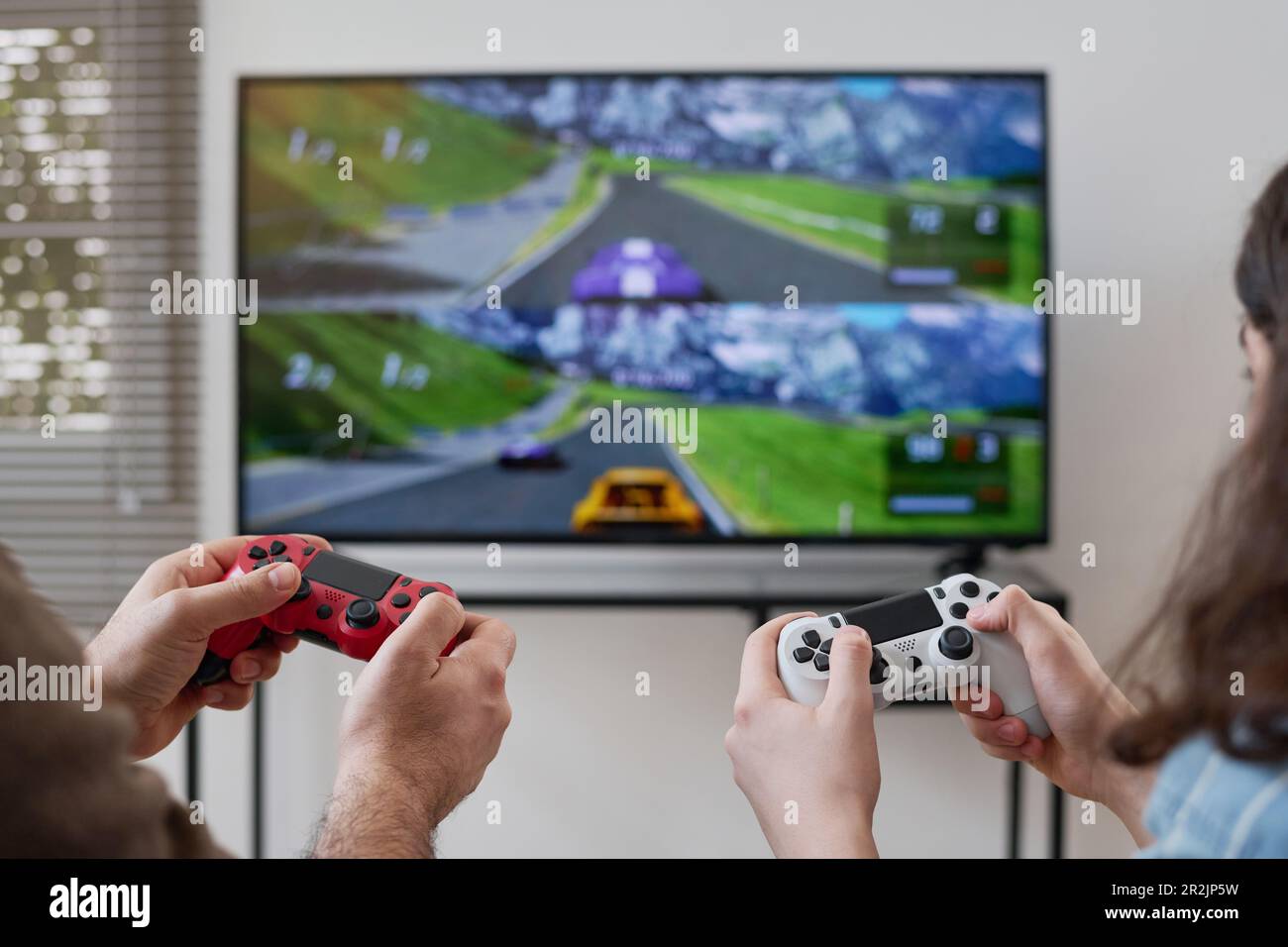 Rear view of teenage boy playing video game together with his dad while ...