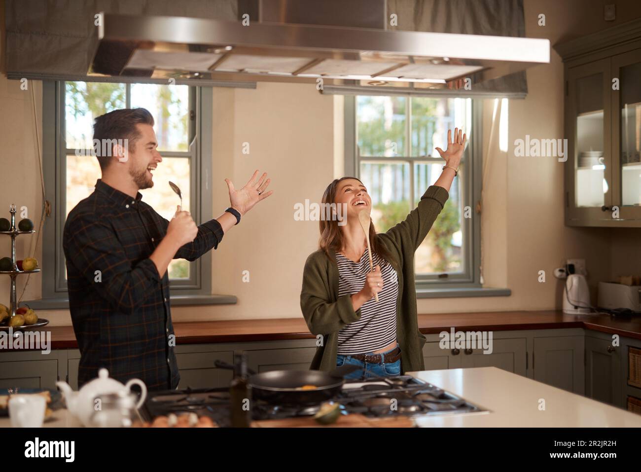 Food, sing and a funny couple in the kitchen of their home, having fun ...