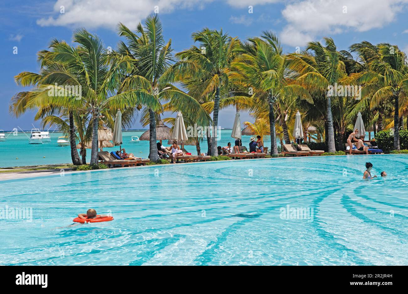 People and palm trees at the pool of Beachcomber Hotel Paradis & Golf ...