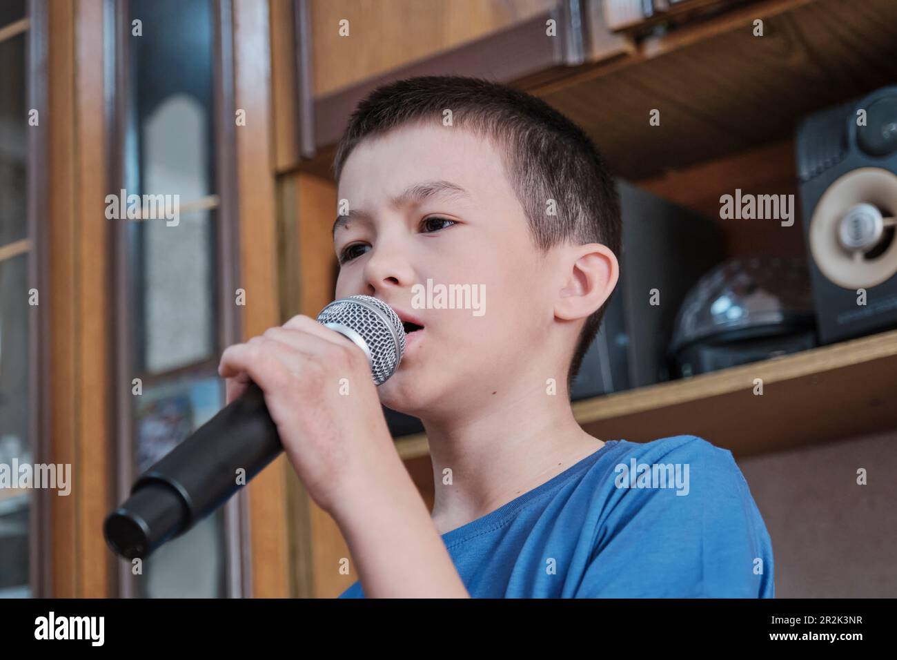 Close-up portrait of serious Asian boy holding microphone singing song ...