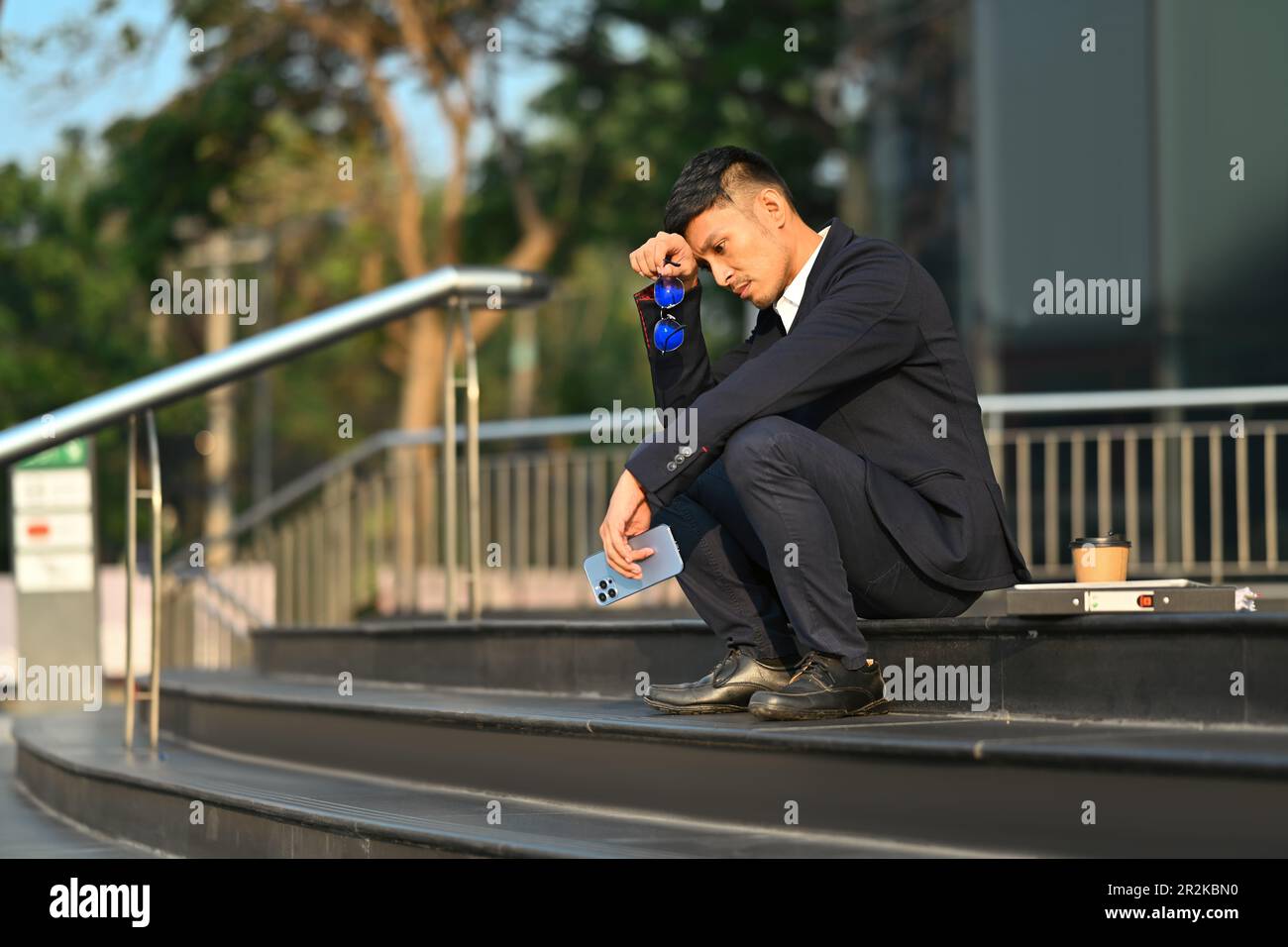 Full length of disappointed man sitting on stairs outside office ...
