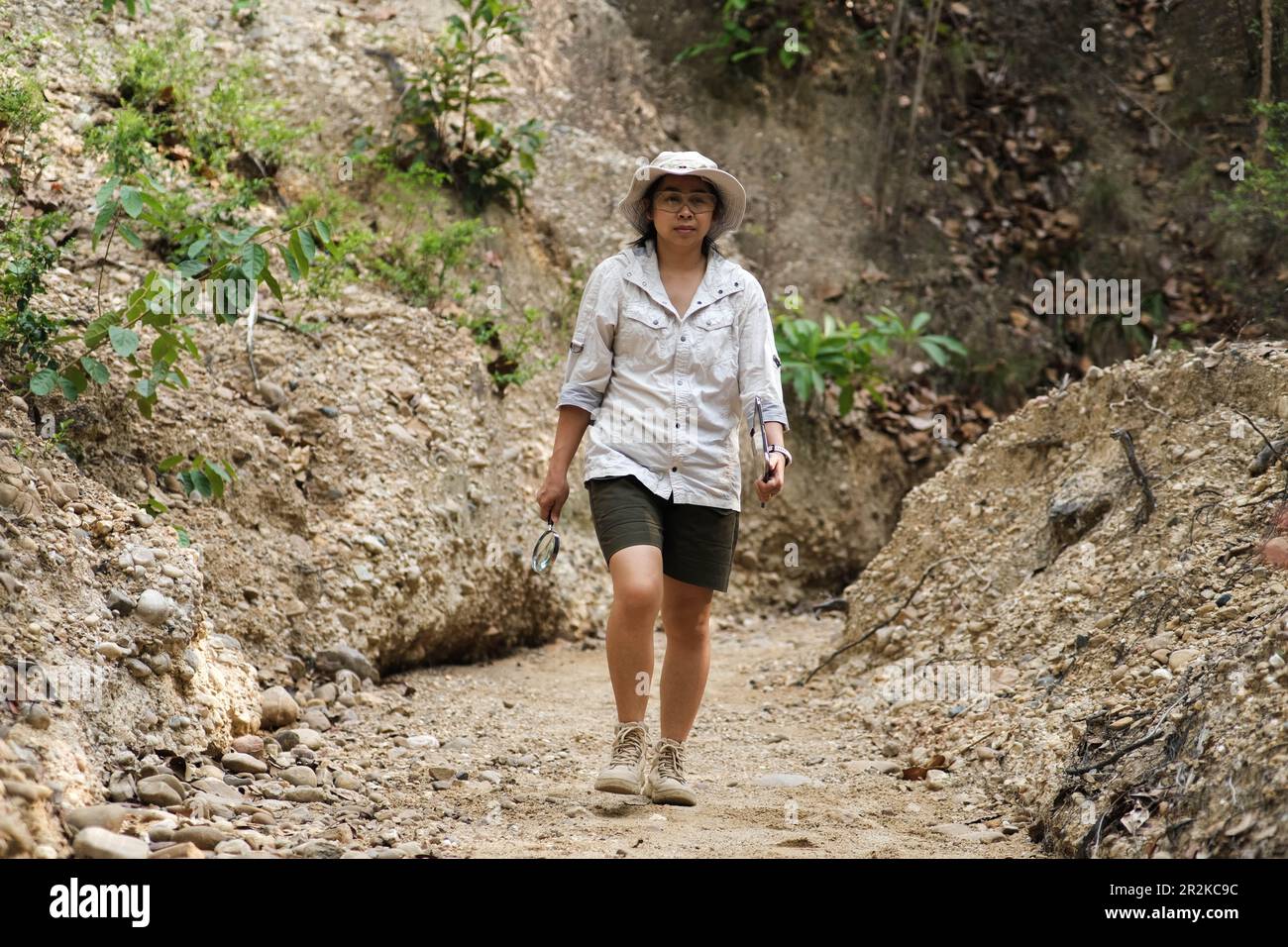 Female geologist holding magnifying glass and laptop working examining ...