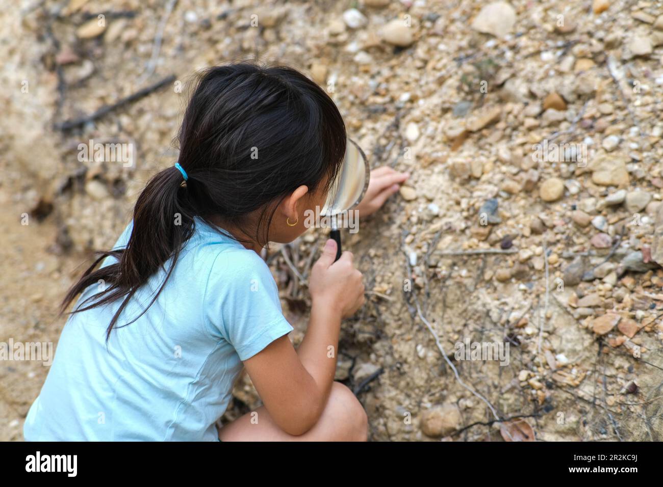 Cute little girl playing with stones and exploring with a magnifying ...
