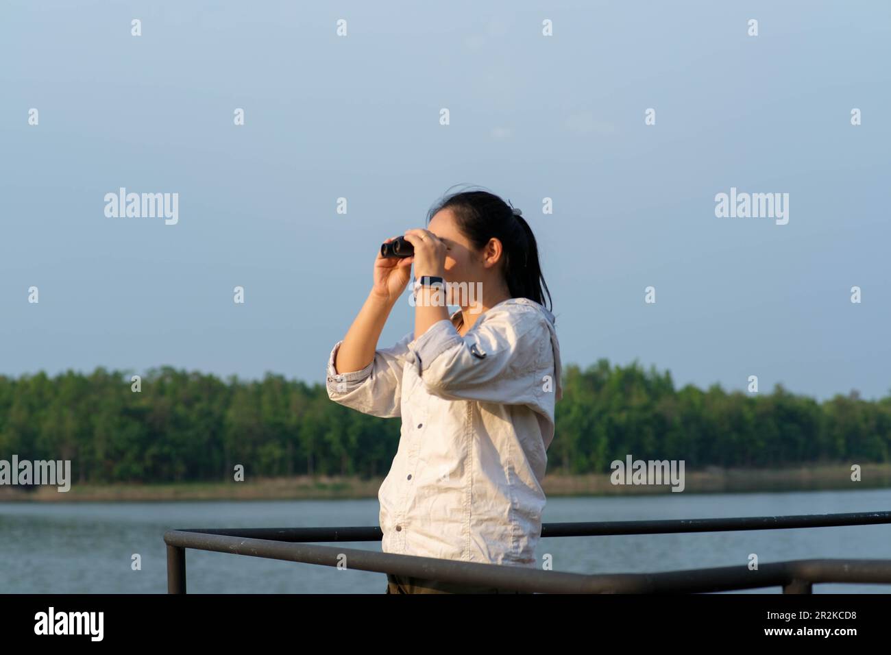 Young female explorer with binoculars exploring nature or watching ...