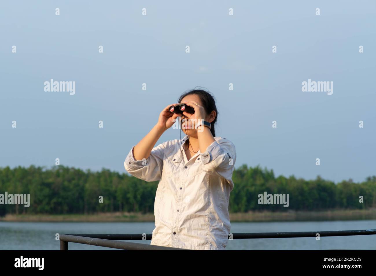 Young female explorer with binoculars exploring nature or watching ...