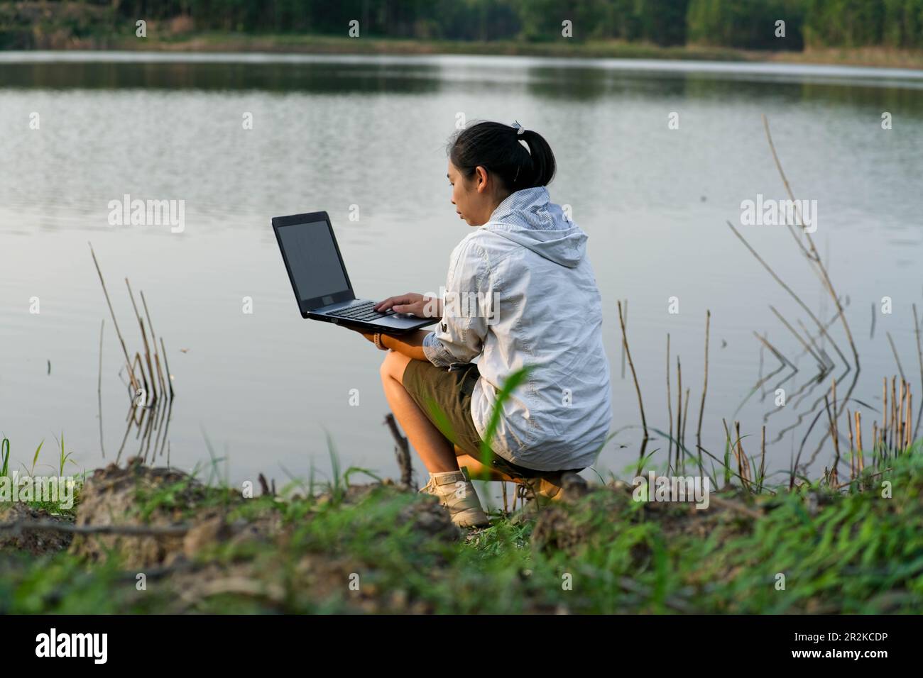 Female environmentalist using laptop computer to record natural water ...