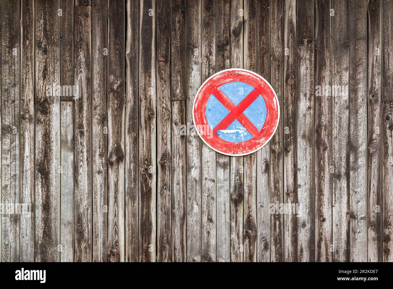 Weathered wooden wall with a hand-painted no parking or no standing ...