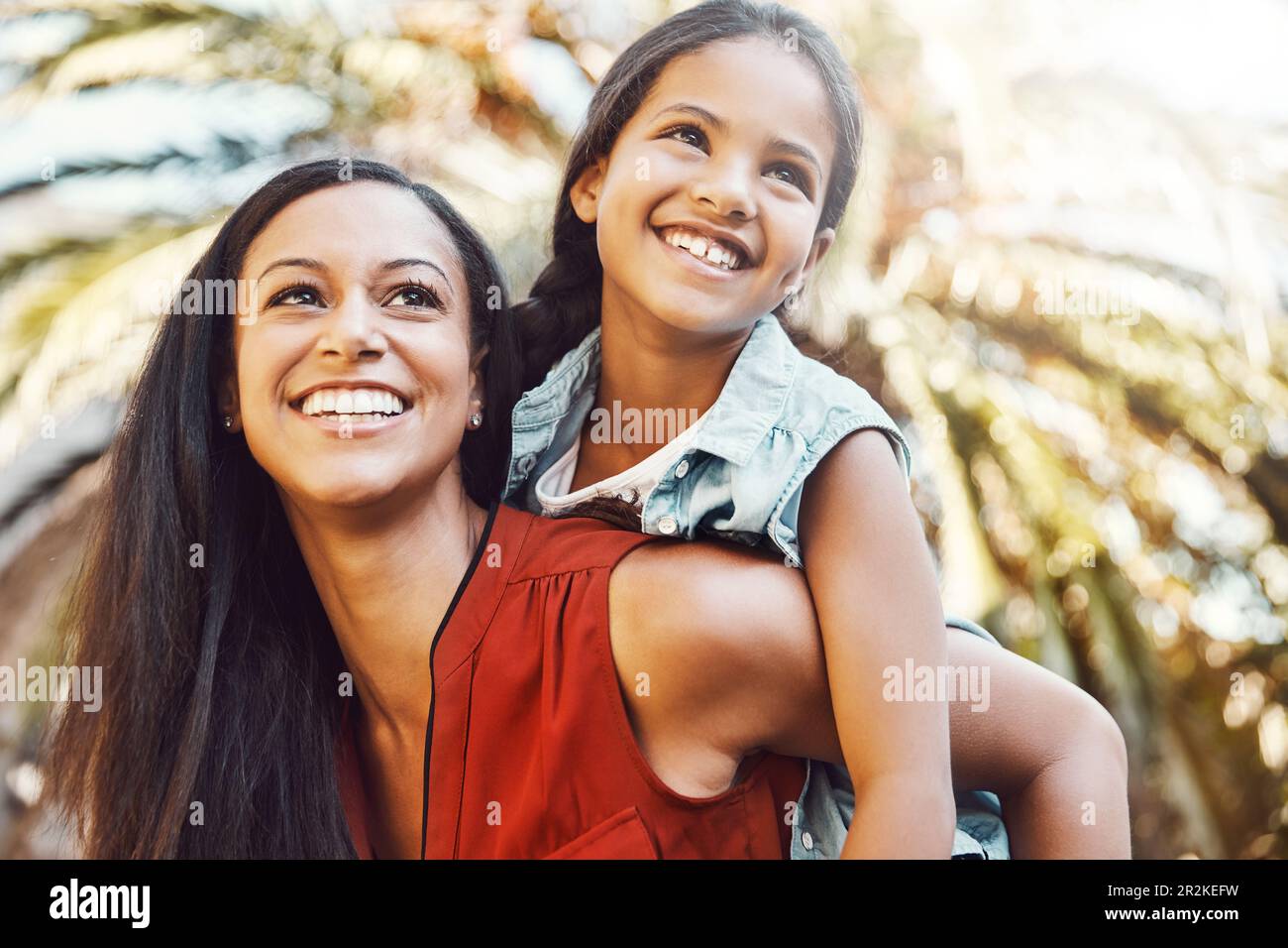 Happy, outdoor and mother giving her child piggyback ride in the garden ...