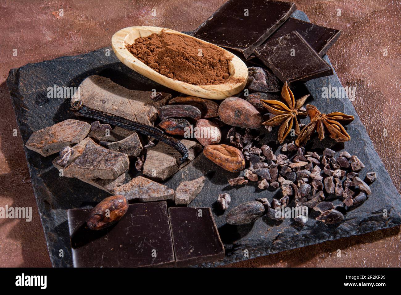 Black chocolate tablet chopped on a slate slab, accompanied by cocoa ...