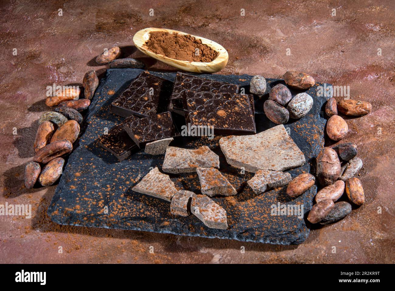 Black chocolate tablet chopped on a slate slab, accompanied by cocoa ...