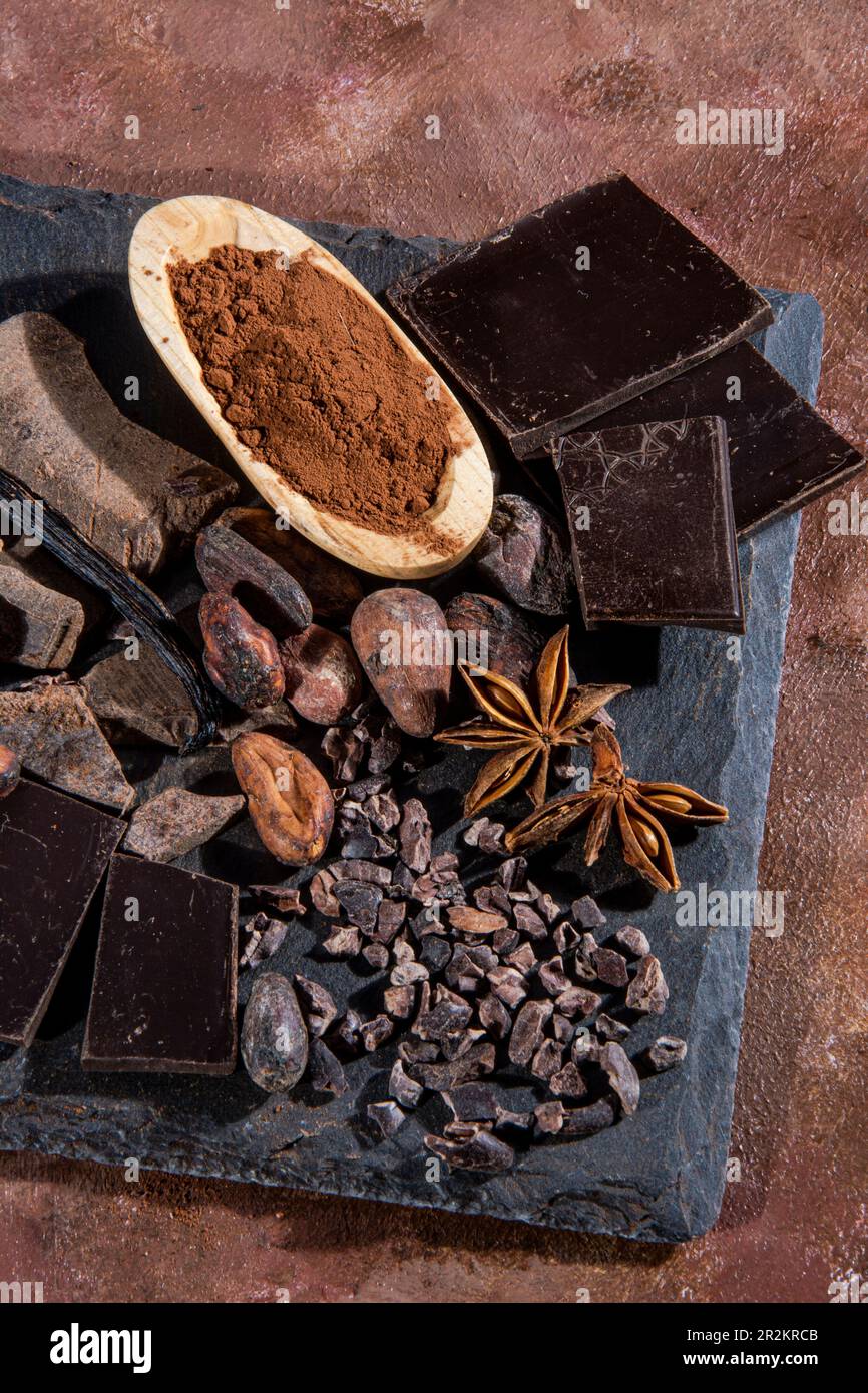 Black chocolate tablet chopped on a slate slab, accompanied by cocoa ...