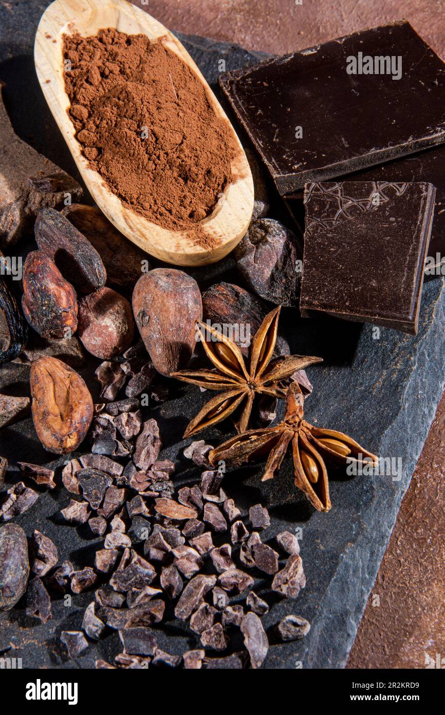 Black chocolate tablet chopped on a slate slab, accompanied by cocoa ...
