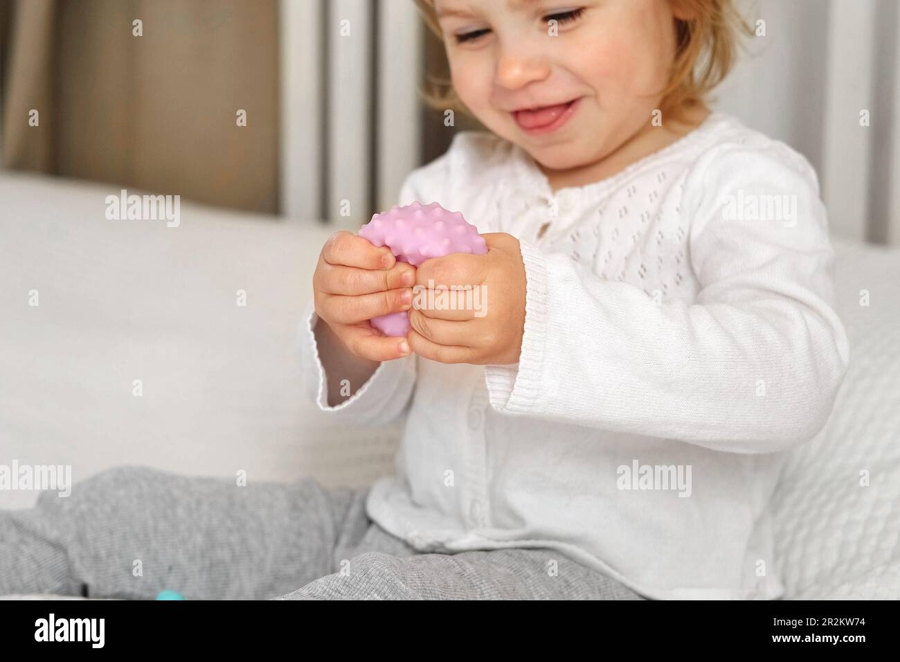 Cute baby girl playing tactile knobby balls. Young child hand plays ...