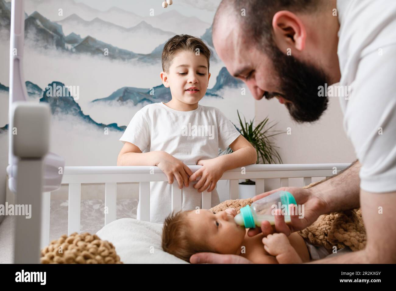 Happy family feed infant child in bed, father and older brother prepare ...