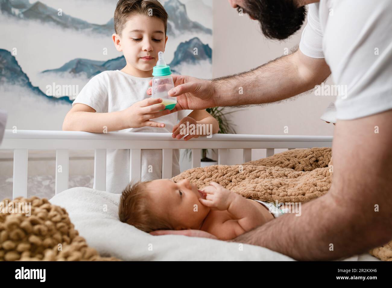 Happy family feed infant child in bed, father and older brother prepare ...