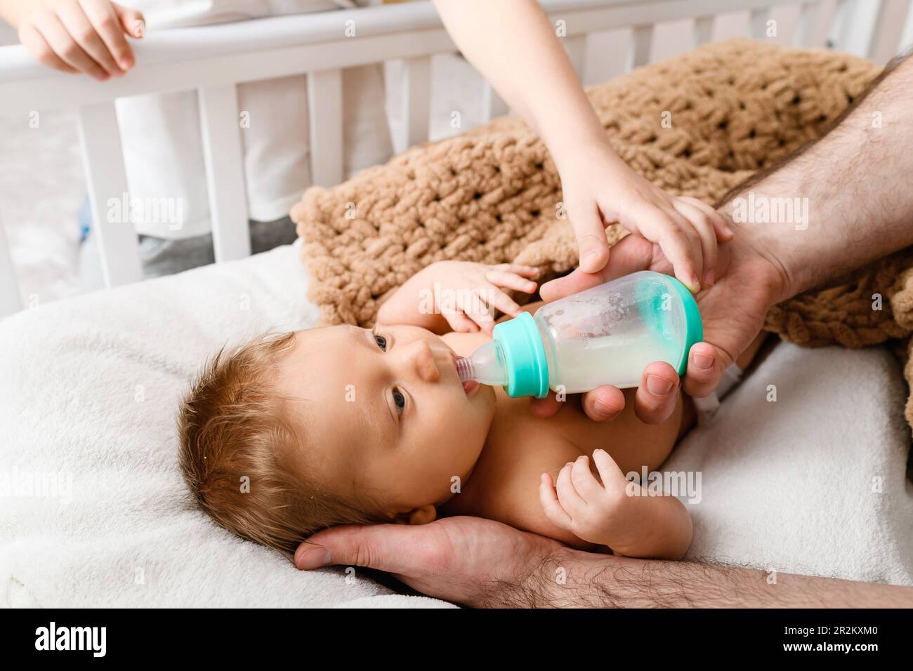 Feeding of baby infant with formula milk in eco plastic bottle, hands ...