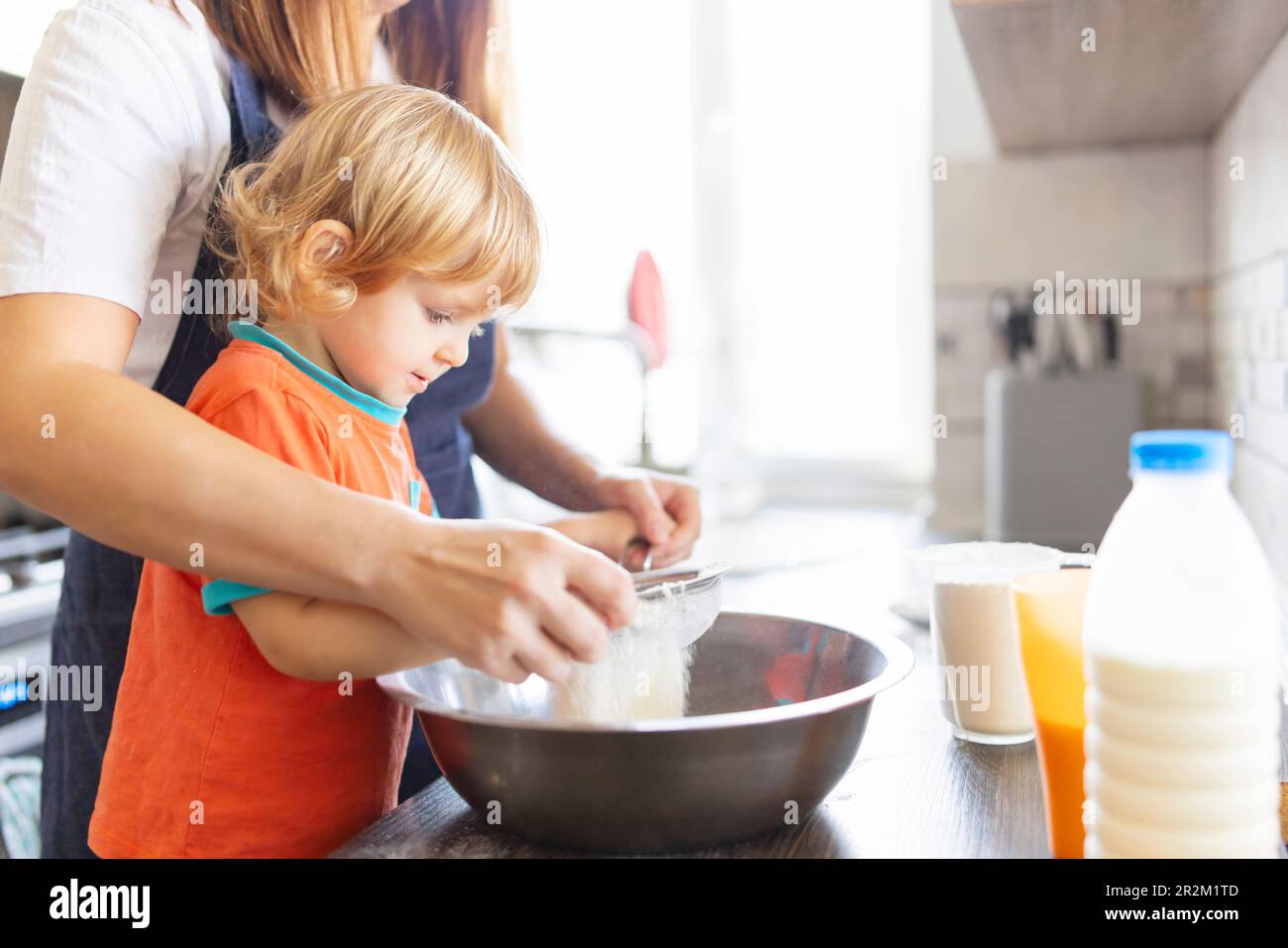 Family in a kitchen. Mother and child sieving flour into a bowl Stock ...