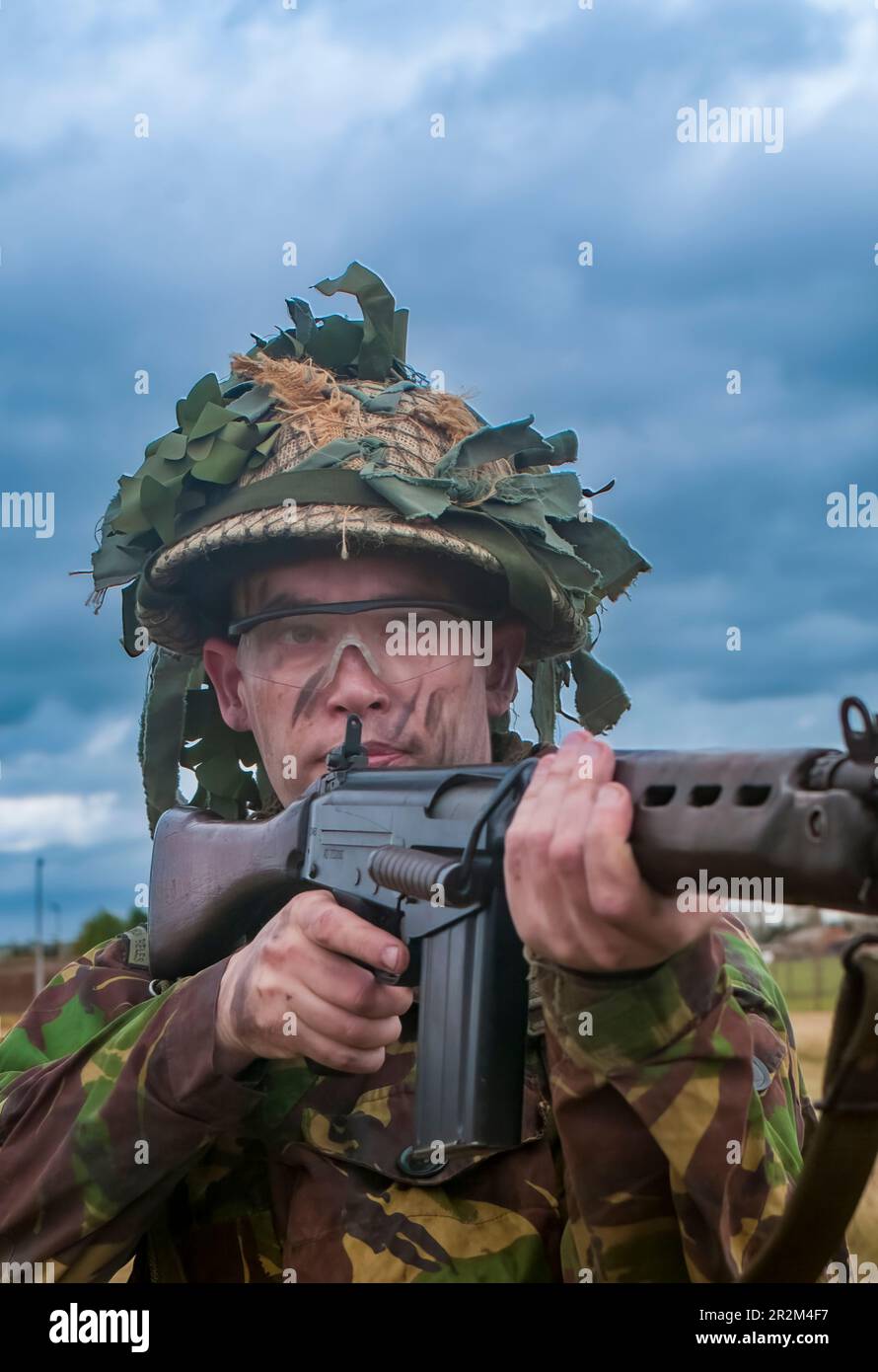 1970 British Army soldier in camouflage suit and steel helmet carrying ...