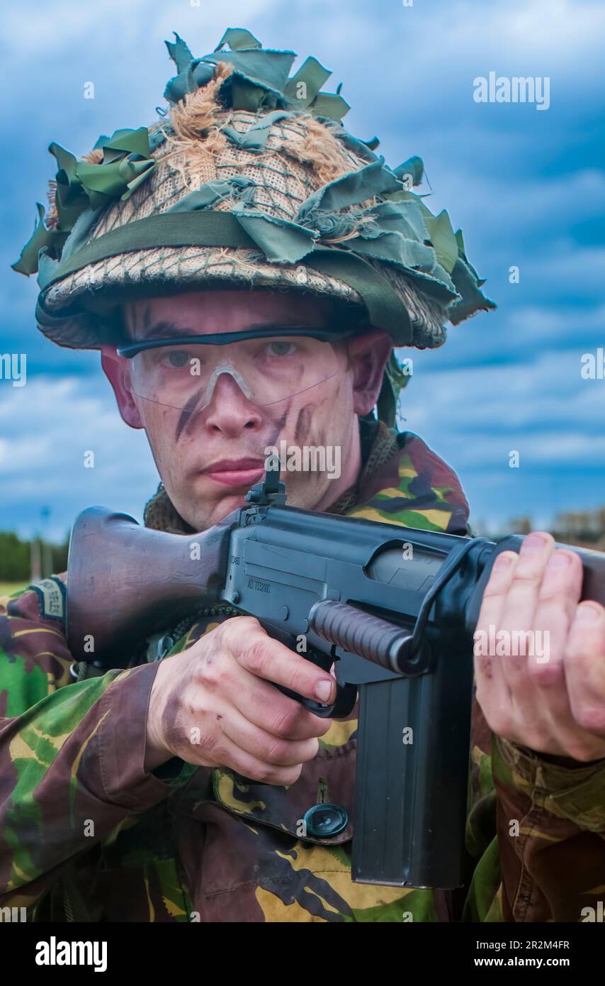 1970 British Army soldier in camouflage suit and steel helmet carrying ...